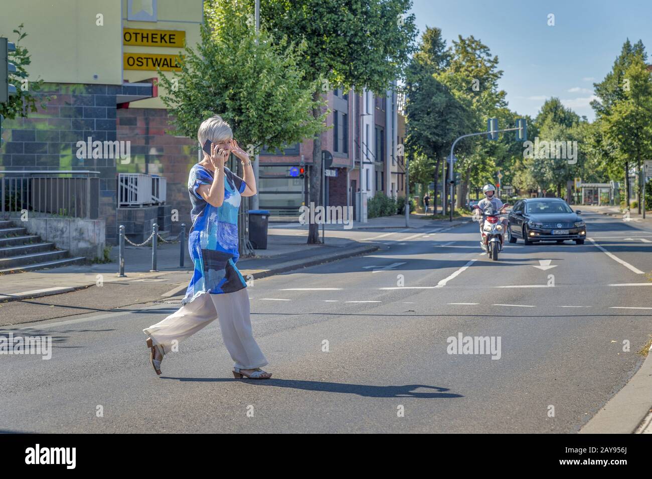 A senior citizen using her smartphone crosses a street Stock Photo - Alamy