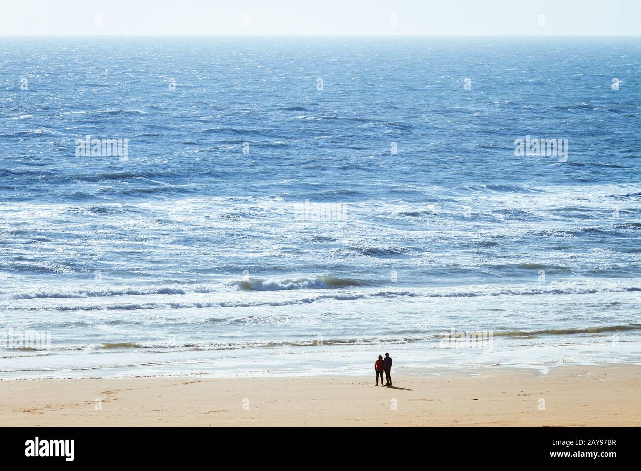 Couple at the beach watching the waves and the panoramic view of the ...