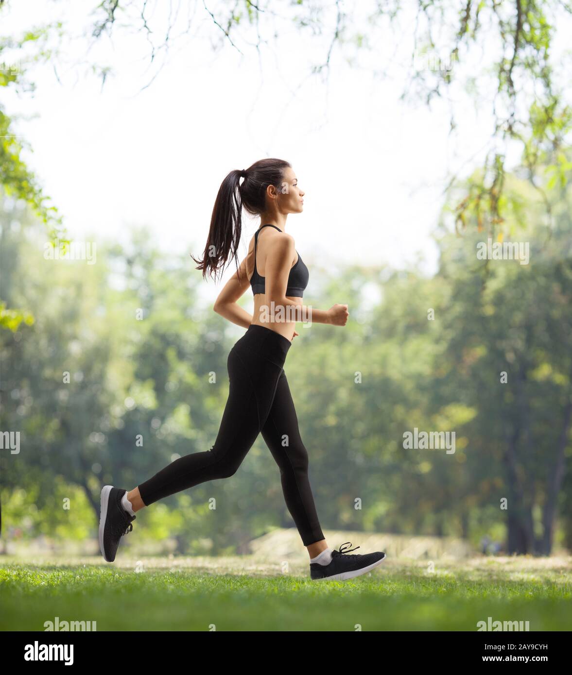 Full length profile shot of a young woman jogging in a park Stock Photo ...