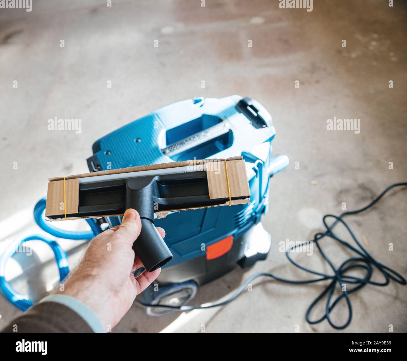 Overhead view of male hand holding new unboxed unpacked vacuum cleaner ...