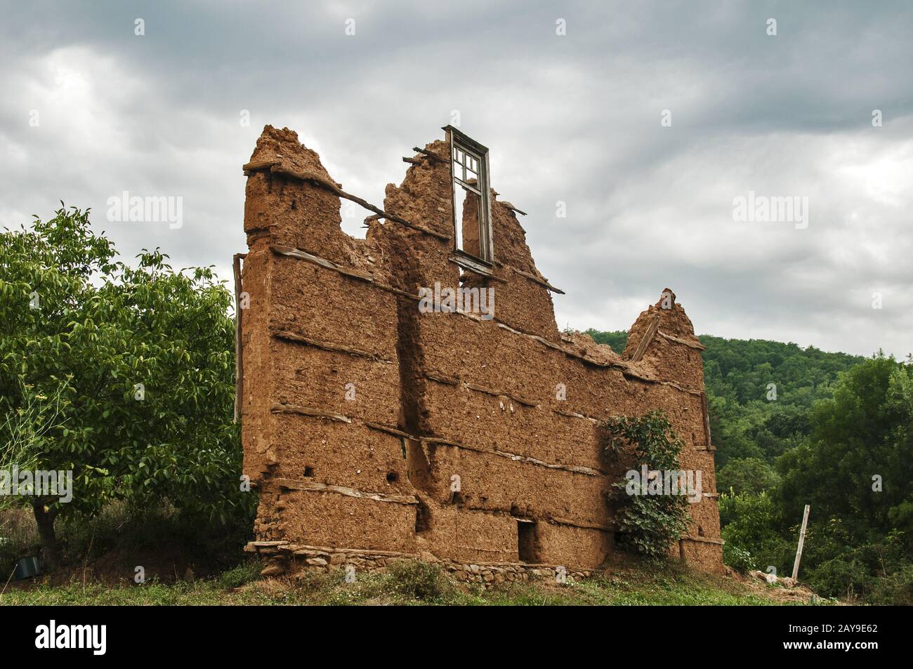 Brick wall with adobe clay plaster and broken window frame of ruined ...