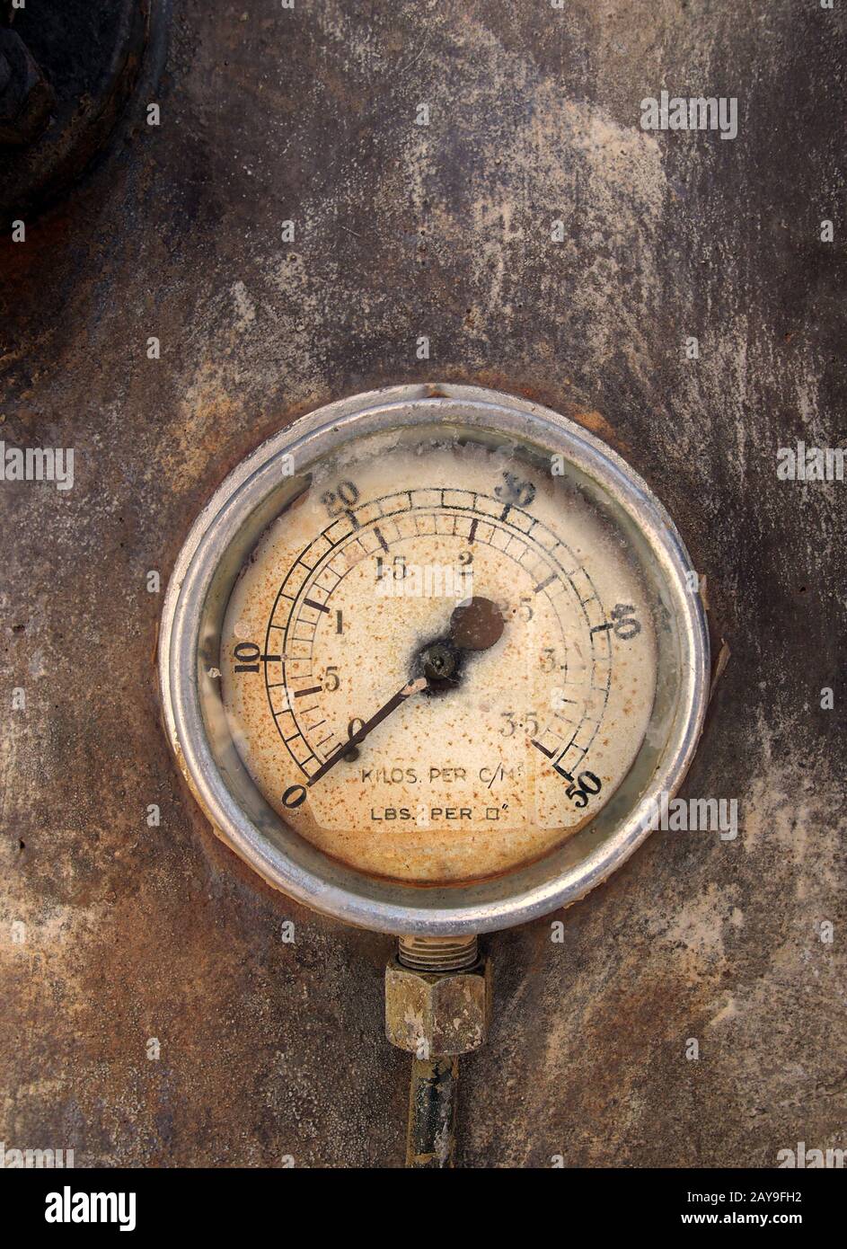 an old round pressure meter with numbers on the gauge on a rusty metal ...