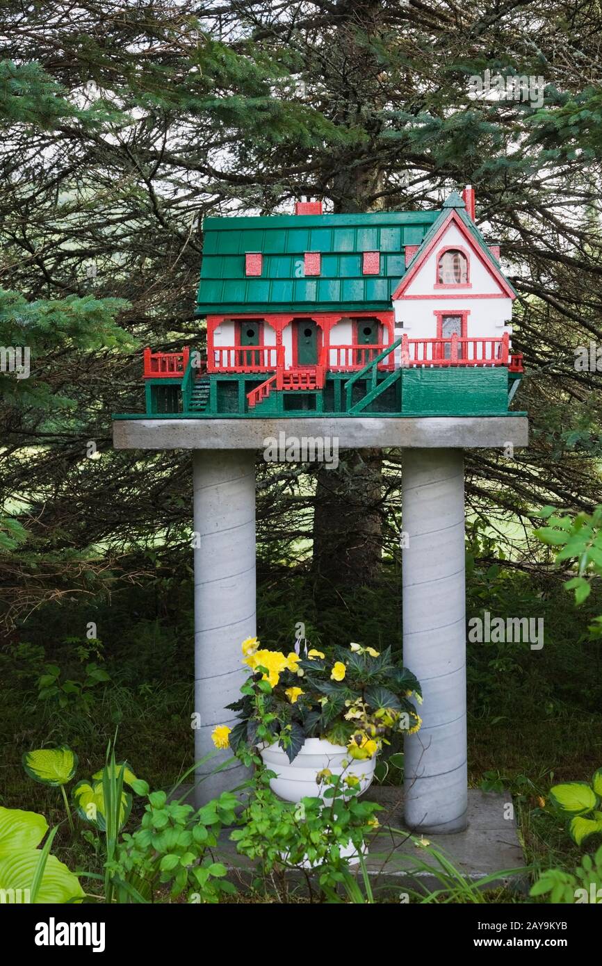 White, green and red painted wooden birdhouse on top of elevated ...