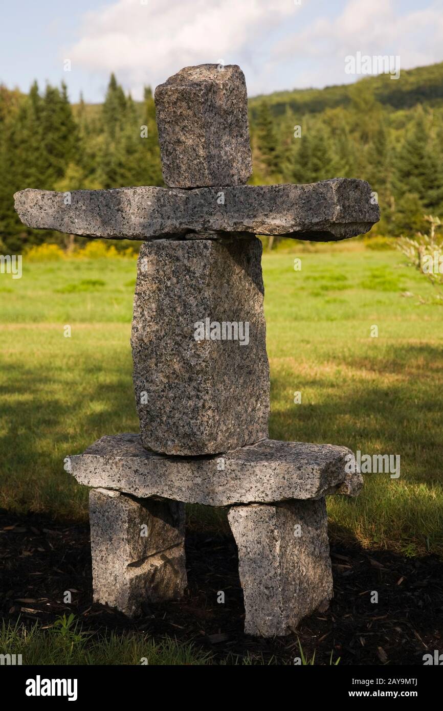 Stacked granite Inukshuk rock sculpture in black mulch border in ...