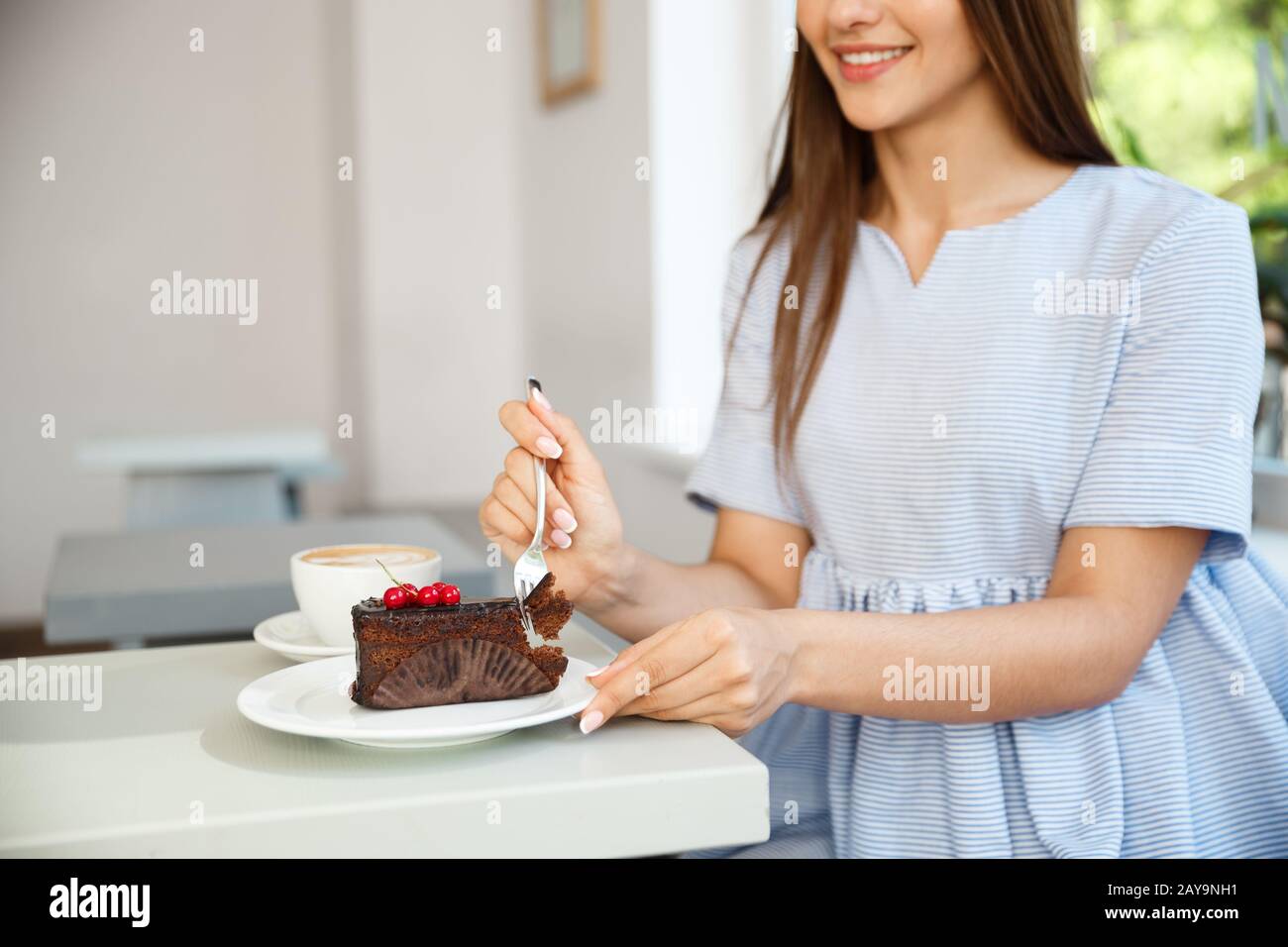 Young attractive Caucasian lady enjoy eating chocolate cake with hot ...