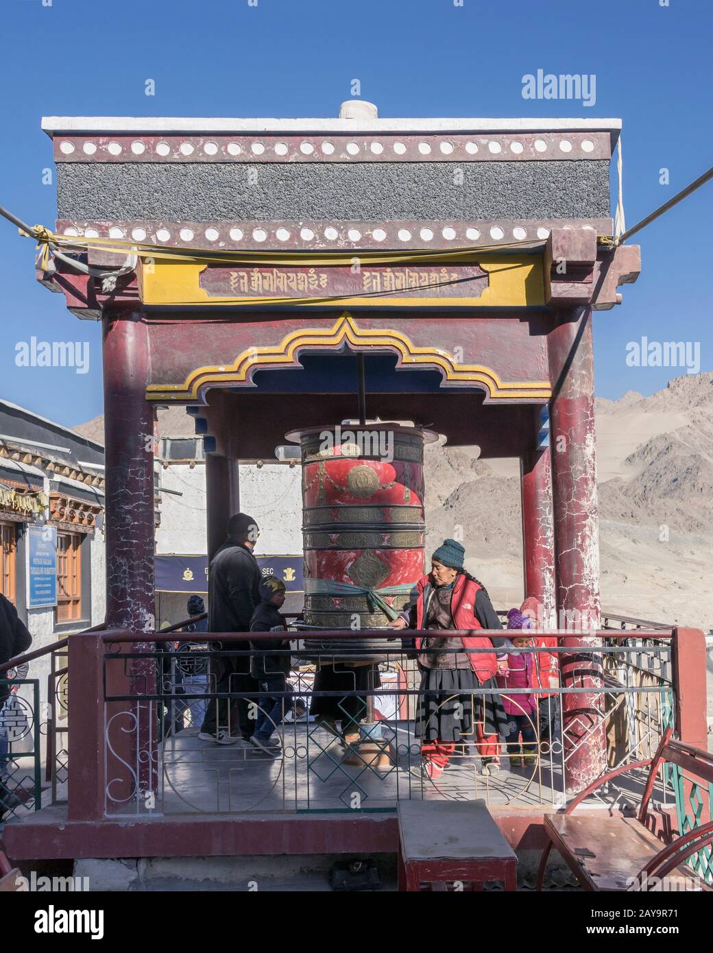 Tibetan grandmother with two grandchildren turning the giant prayer ...