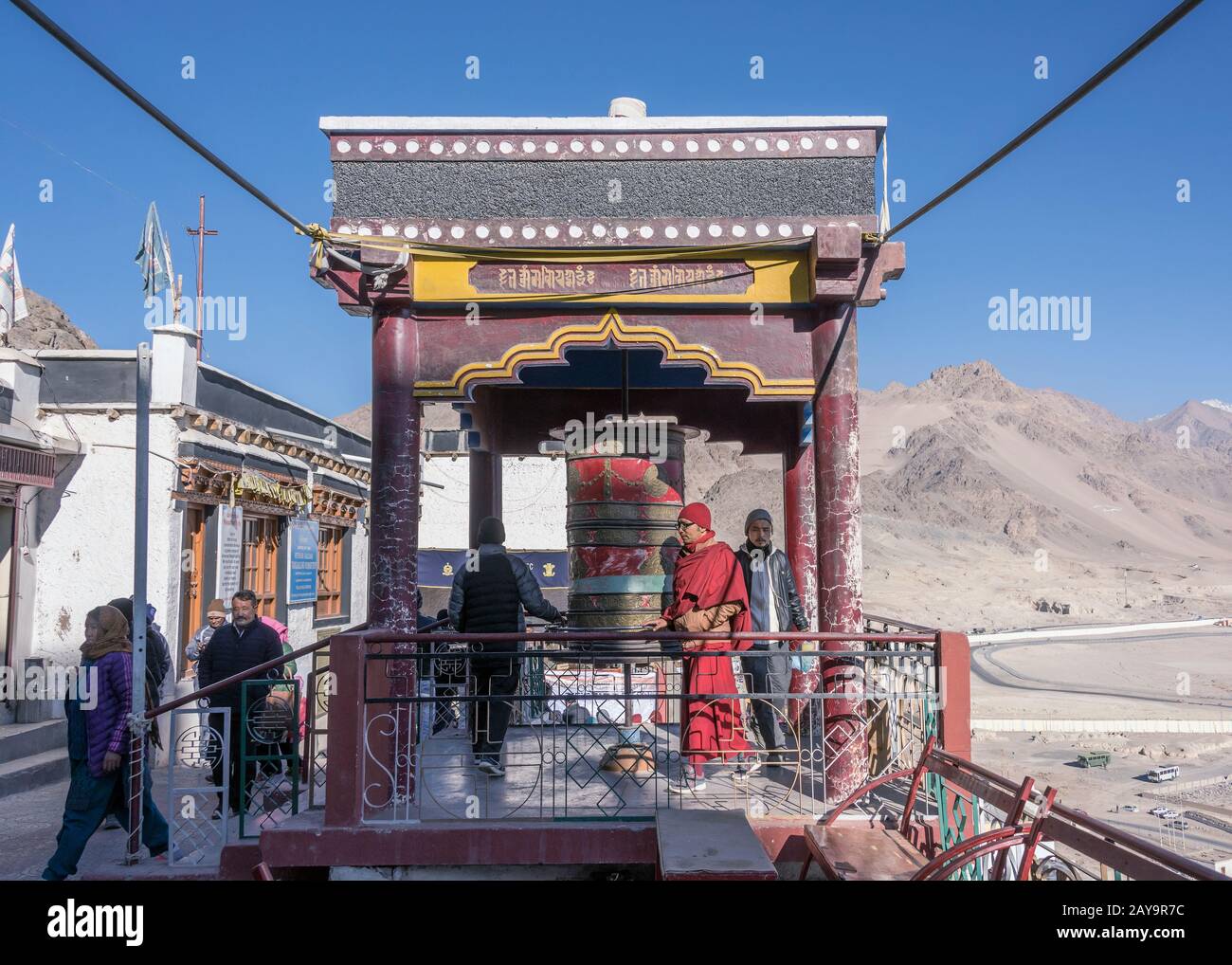 Buddhist monk turning the giant prayer wheel, Spituk Gompa, Leh ...