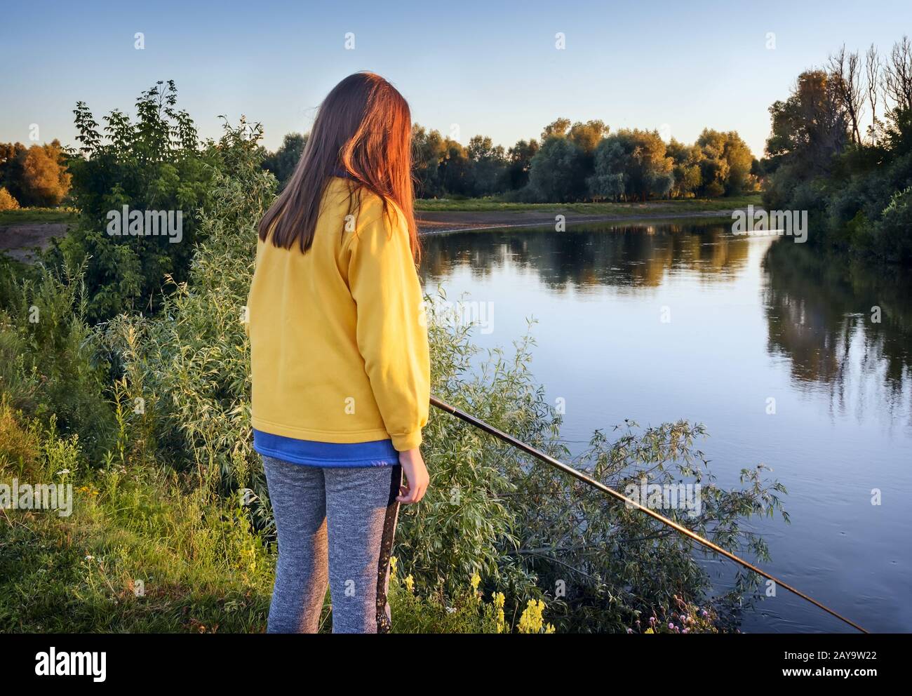 Girl with a fishing rod on the river Bank Stock Photo - Alamy