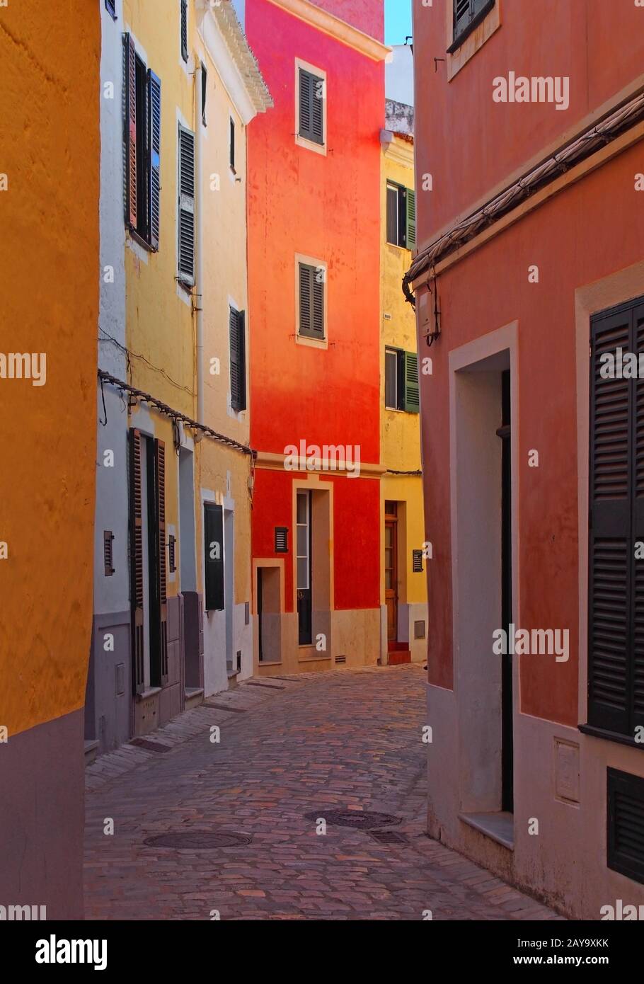 brightly painted traditional houses on a cobbled quiet curved empty ...