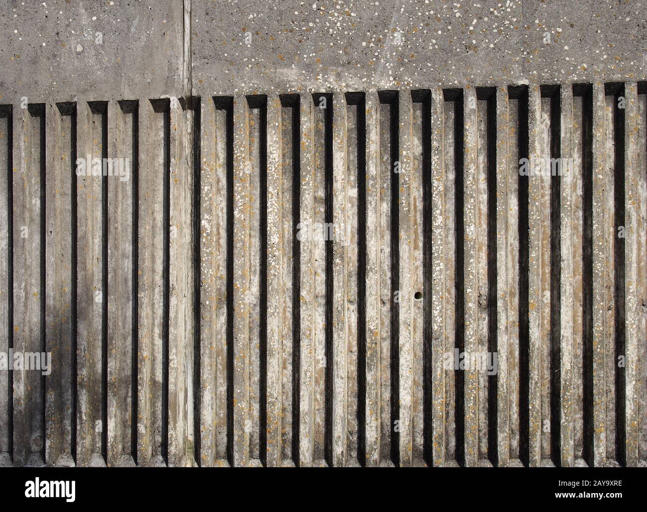 old exterior concrete wall with fluted vertical stripe design with a ...