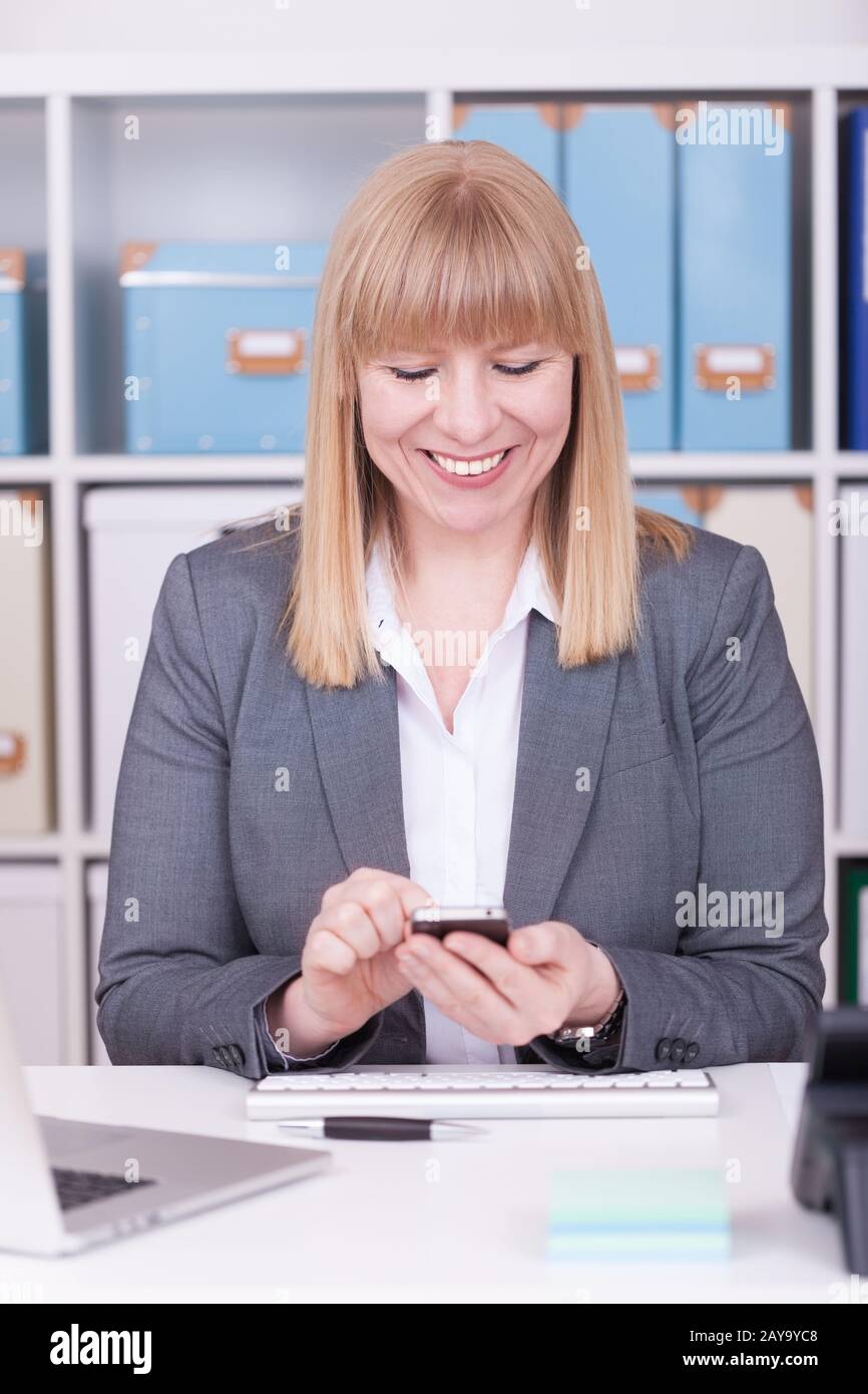Woman at the office typing and messaging with her mobile phone Stock ...