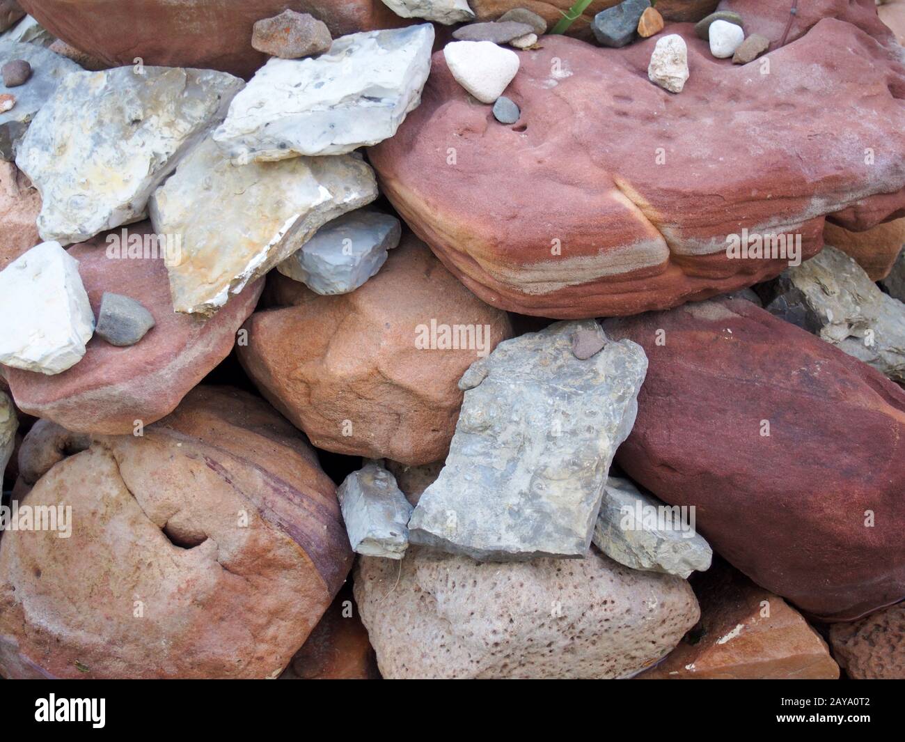 a heap of different colored and textured red and grey beach stones ...