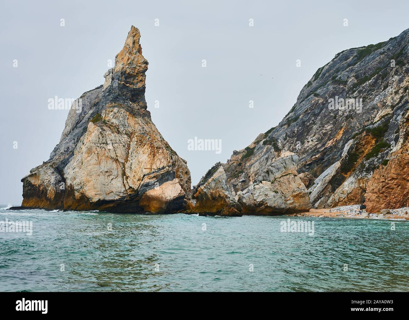 Giant rock at the end of the beach on cloudy day Stock Photo - Alamy