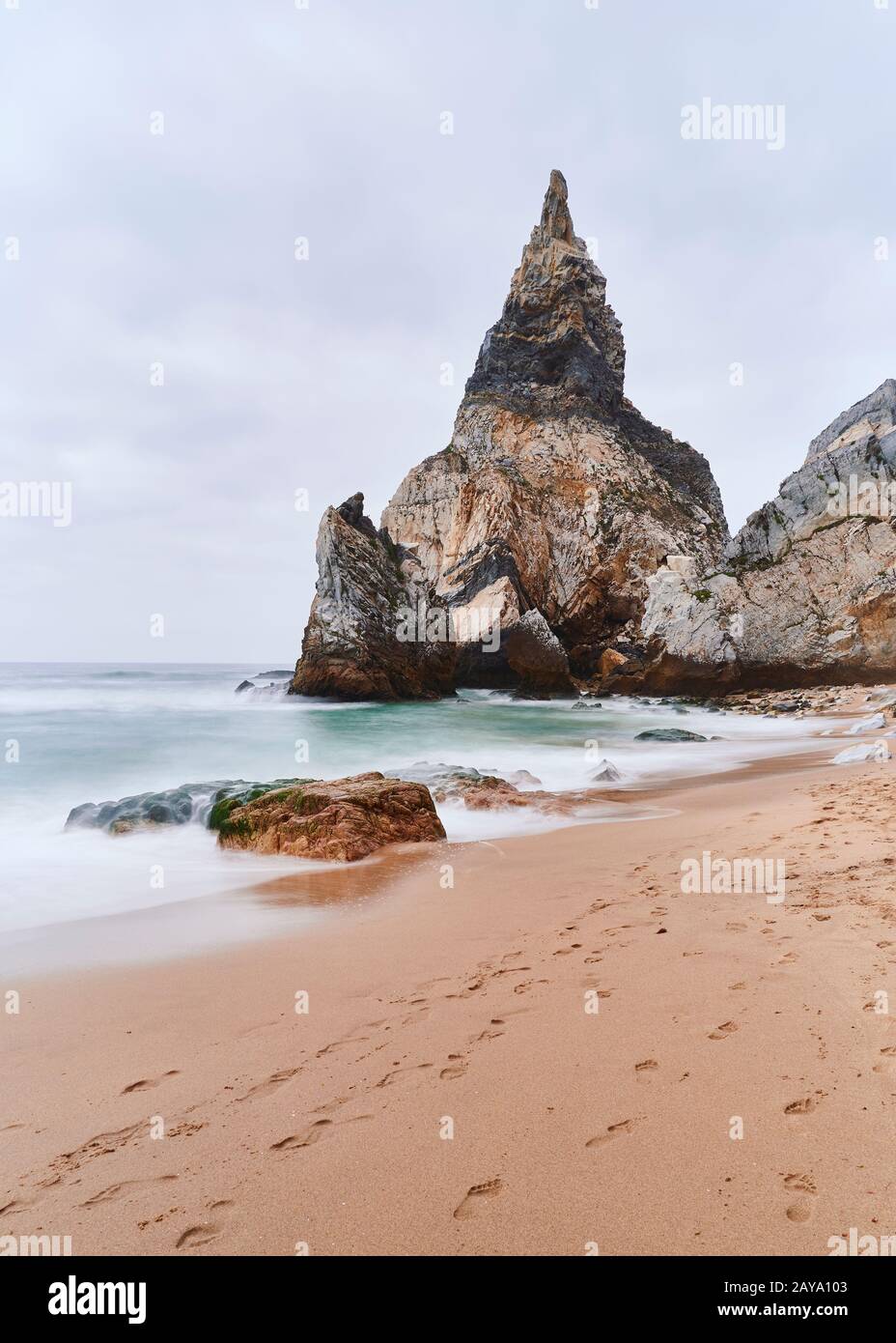 Giant rock at the end of the beach on cloudy day Stock Photo - Alamy