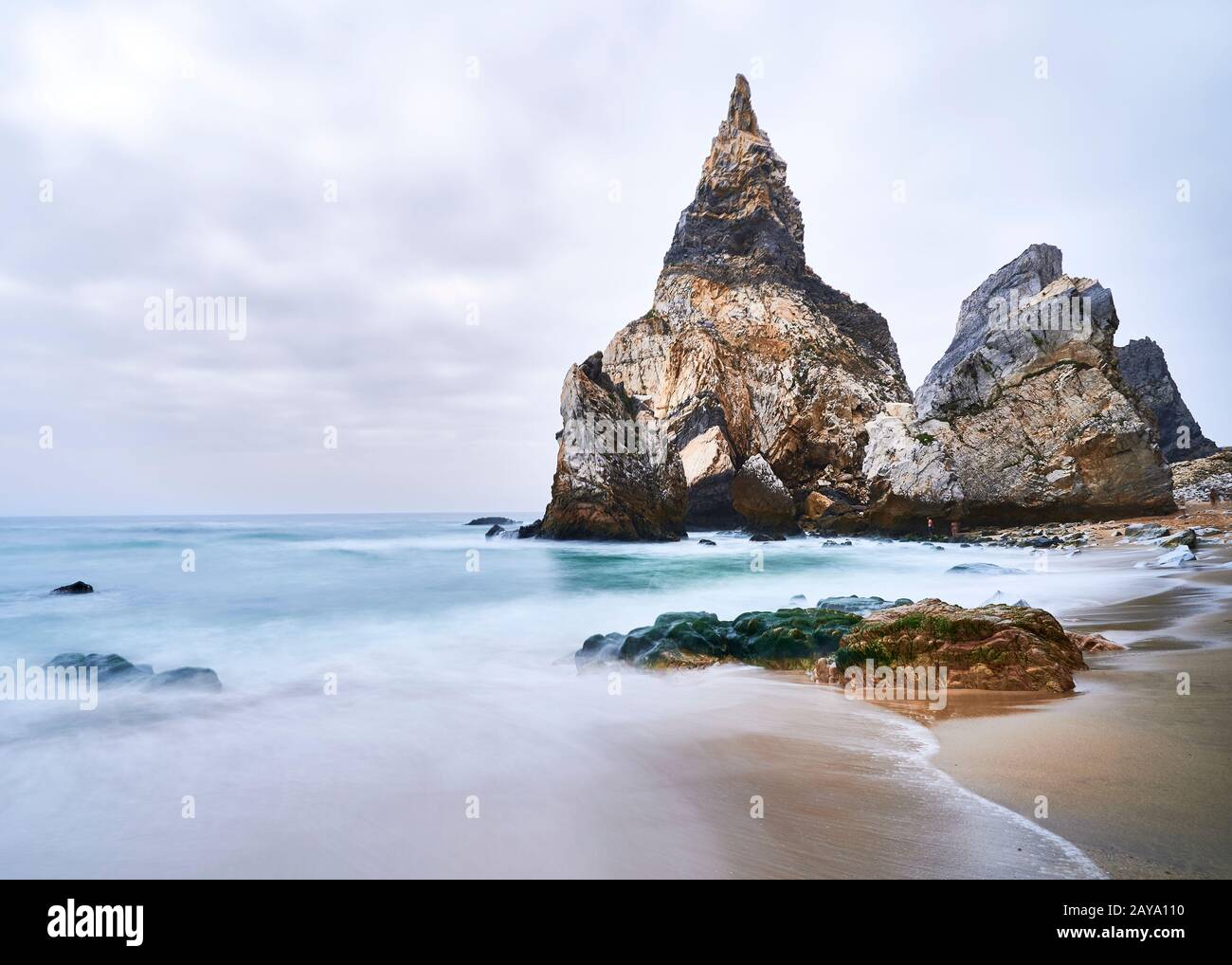 Giant rock at the end of the beach on cloudy day Stock Photo - Alamy
