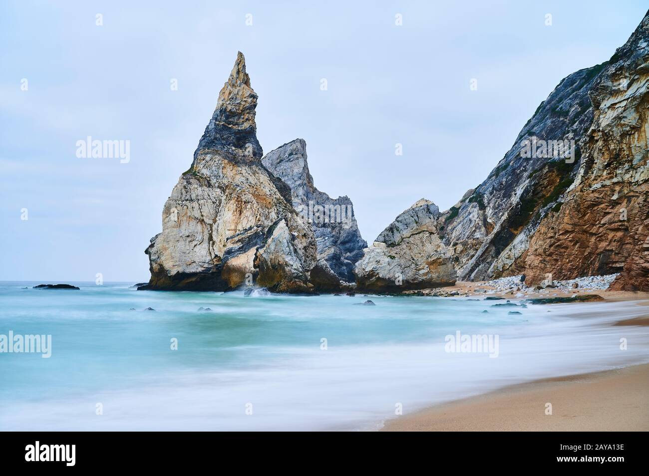 Giant rock at the end of the beach on cloudy day Stock Photo - Alamy