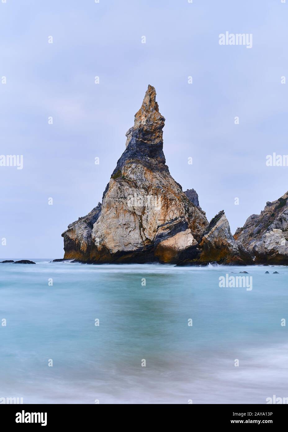 Giant rock at the end of the beach on cloudy day Stock Photo - Alamy