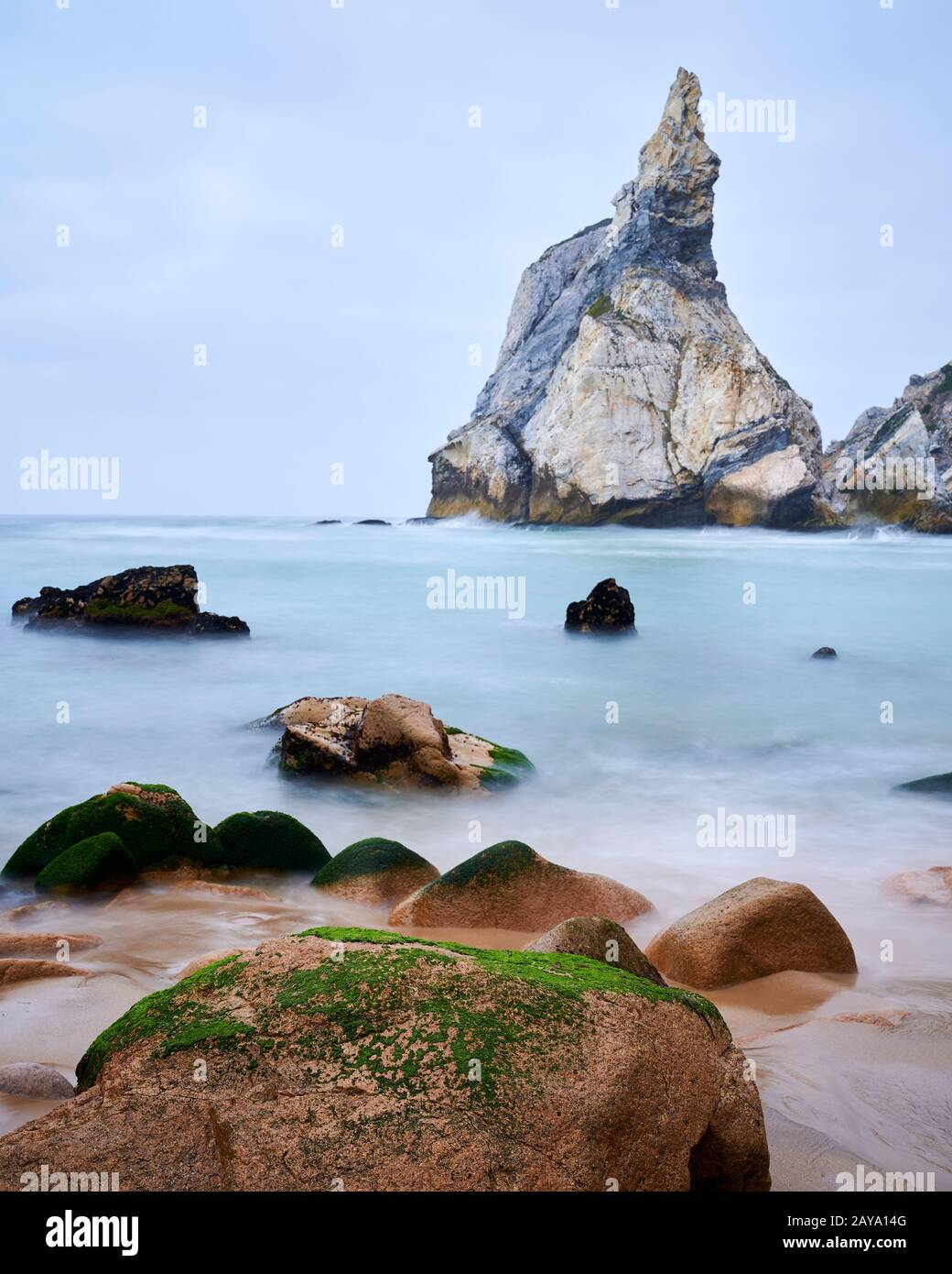 Giant rock at the end of the beach on cloudy day Stock Photo - Alamy