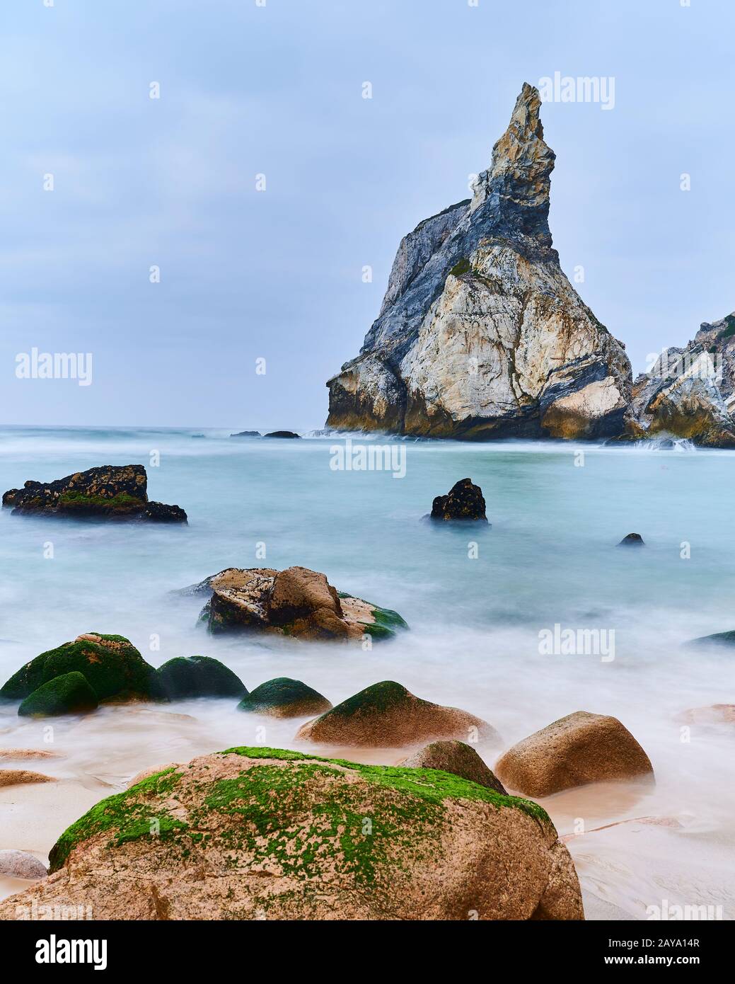Giant rock at the end of the beach on cloudy day Stock Photo - Alamy