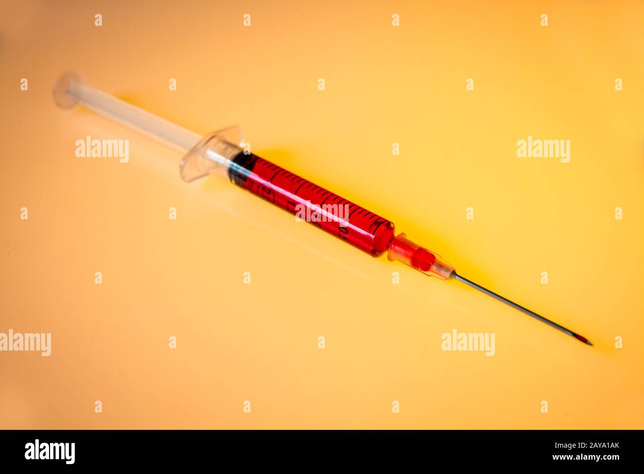 Syringe with blood on orange background Stock Photo - Alamy