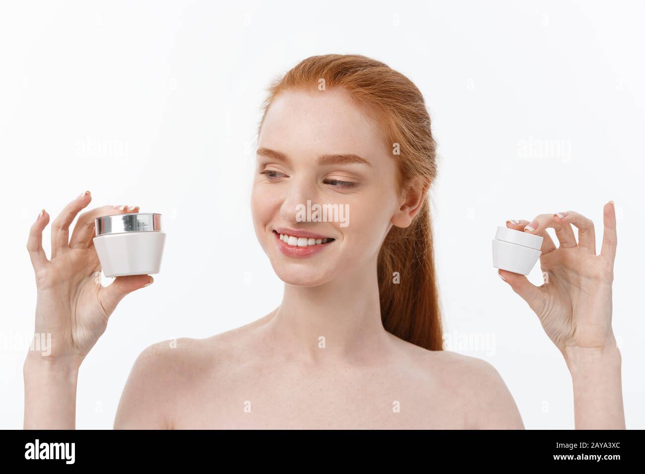 portrait of beautiful woman smiling while taking some facial cream ...