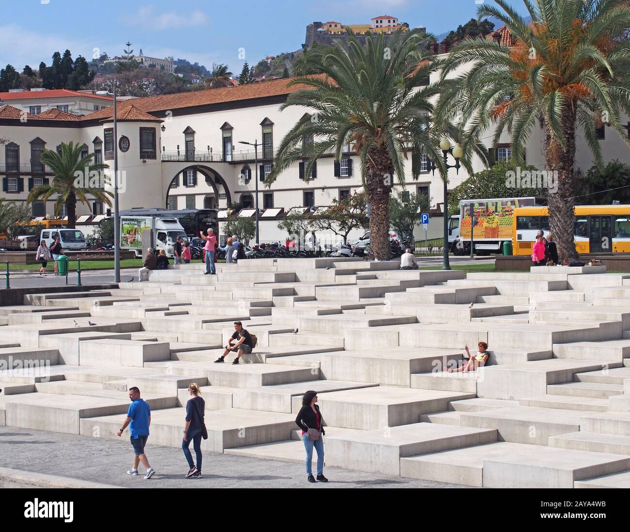 tourists sitting and passers by on the concrete steps of the marina in ...