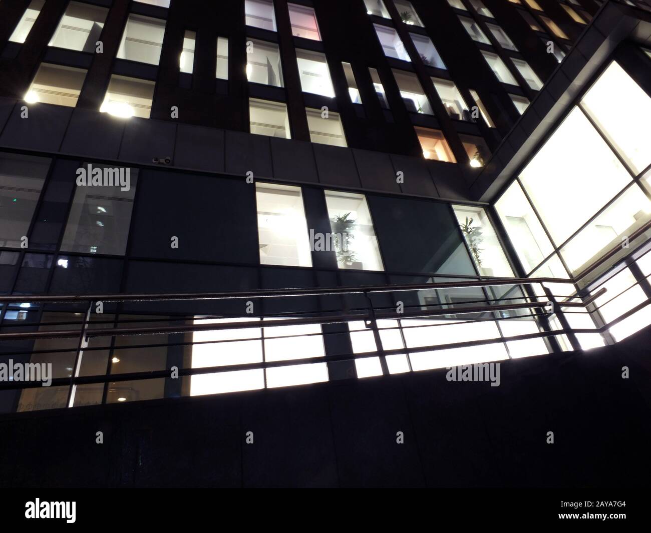 the entrance ramp and windows of a large office building brightly ...