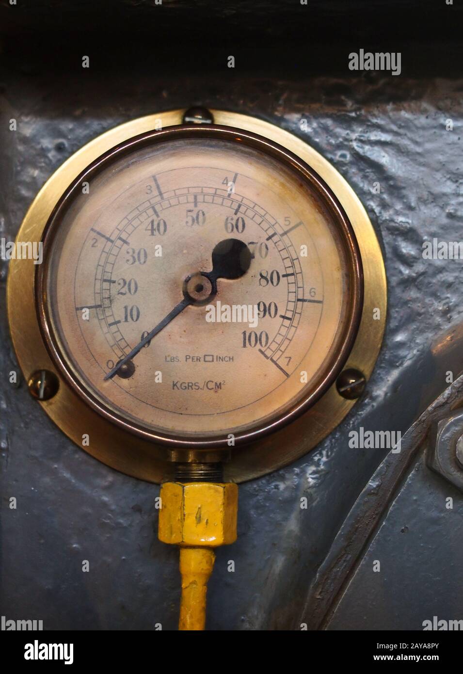 an old brass pressure meter with a round scale with numbers on an aged ...
