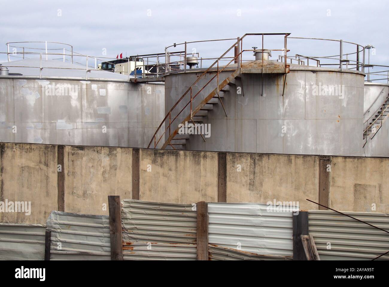 old metal industrial storage tanks with rusty inspection ladders and ...