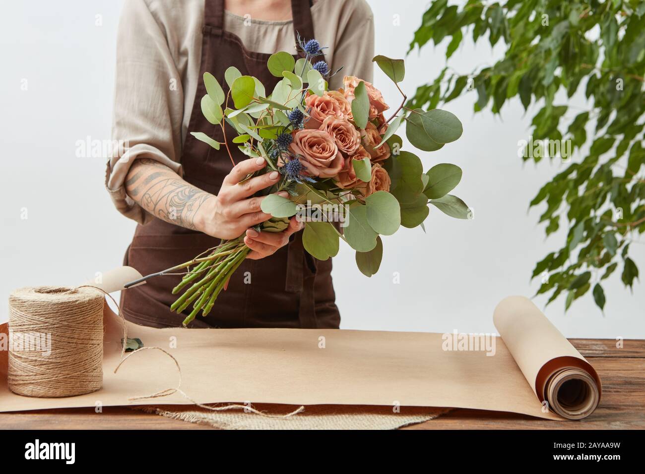 Young woman florist is making bouquet with fresh flowers roses living ...