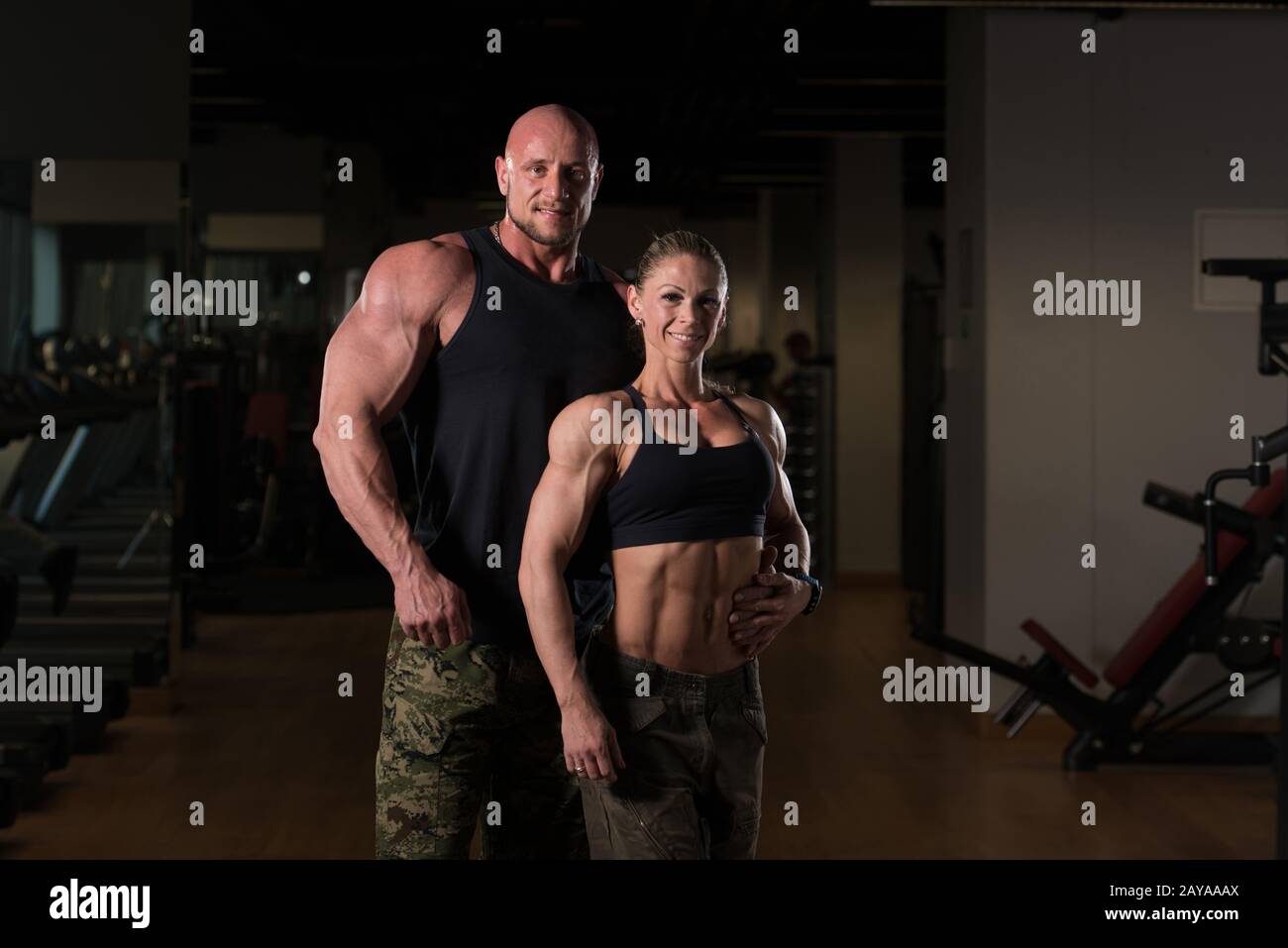 Fitness Couple Standing Strong In The Gym And Flexing Muscles ...
