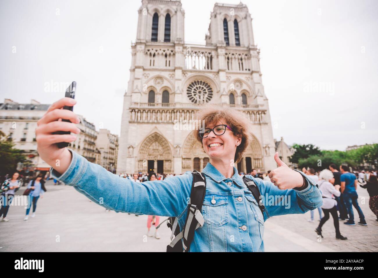 Tourist in Paris making funny selfie near Notre Dame Cathedral ...