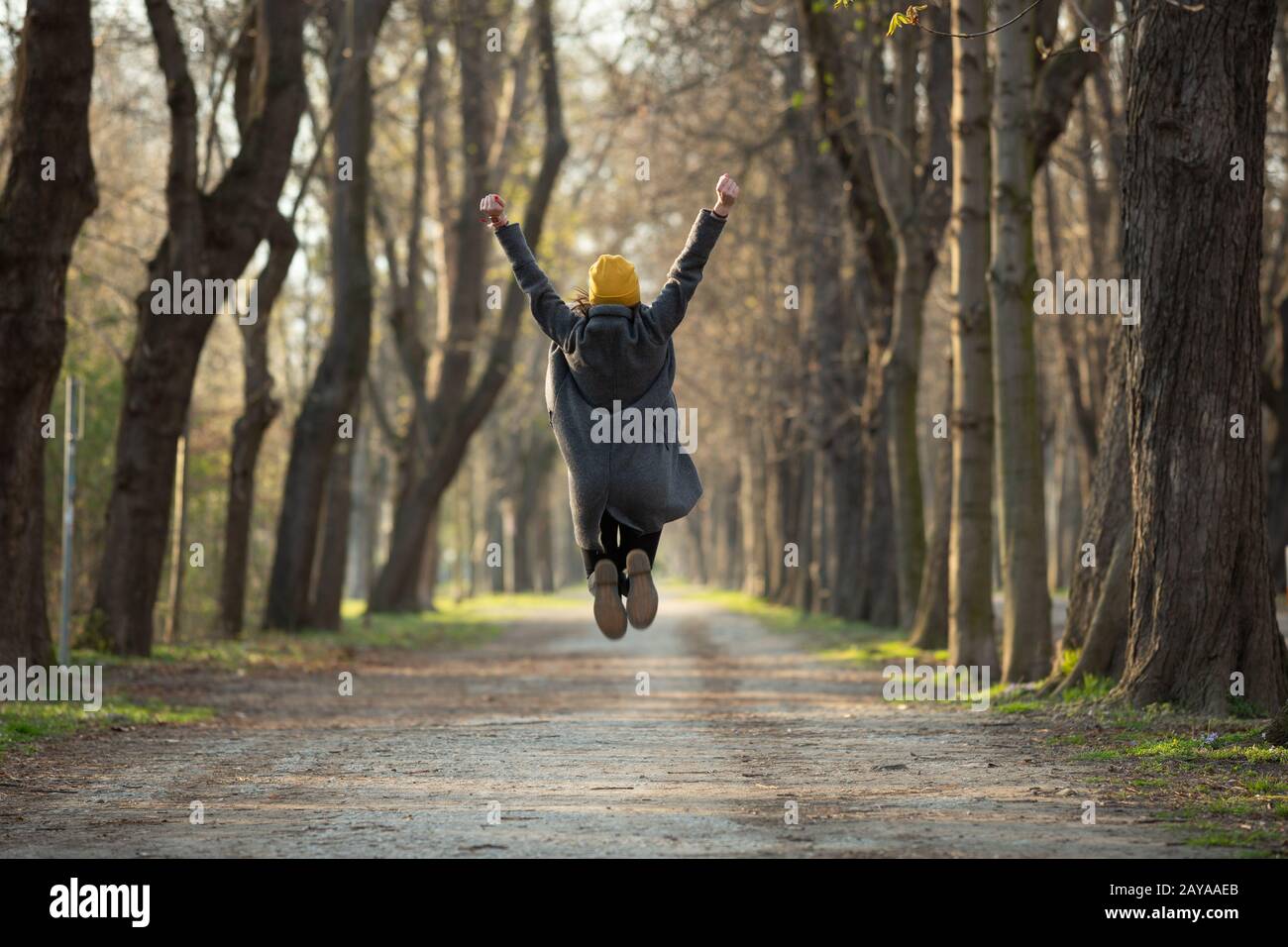 Excited young woman is jumping with arms raised up Stock Photo - Alamy