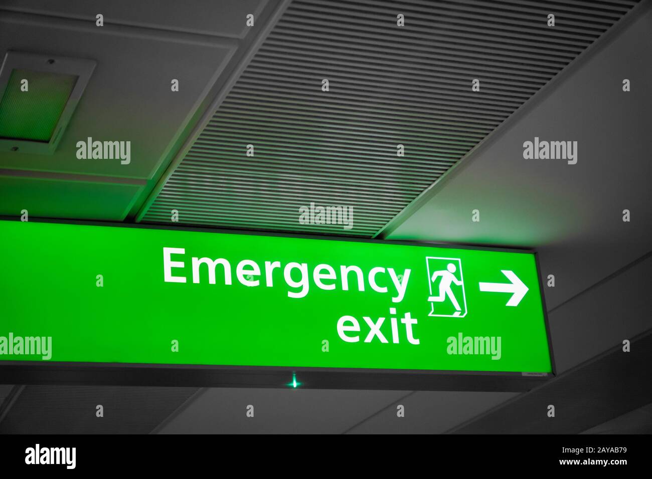 Emergency exit sign glowing green in airport- for safety, fire drill ...