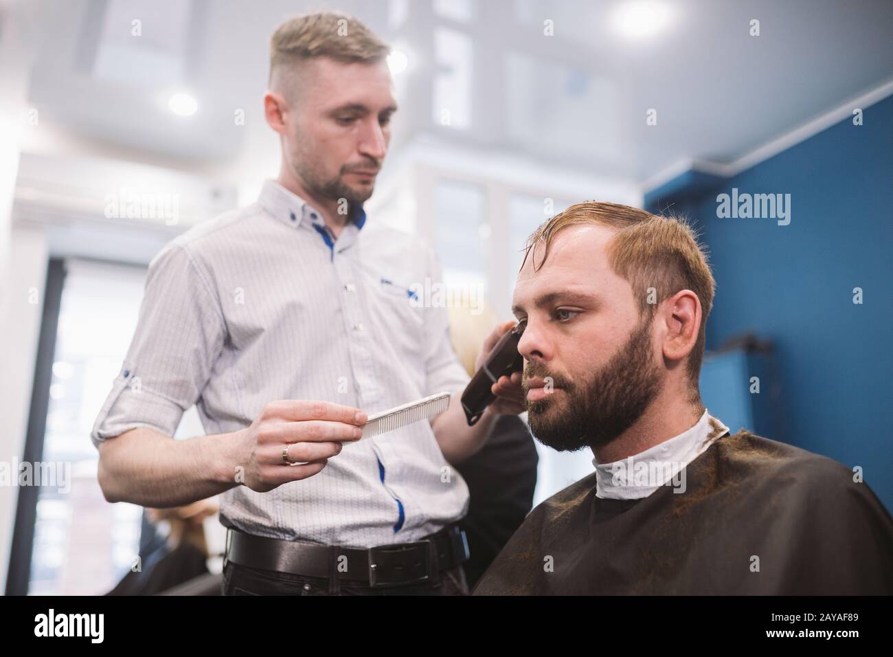 Close up shot of man getting trendy haircut at barber shop. Male ...