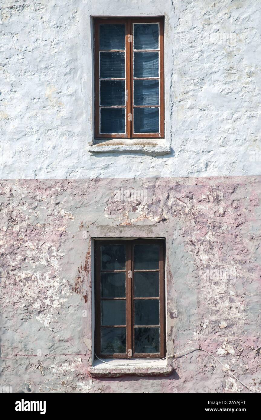 Old vintage countryside house facade with two wooden windows closeup ...