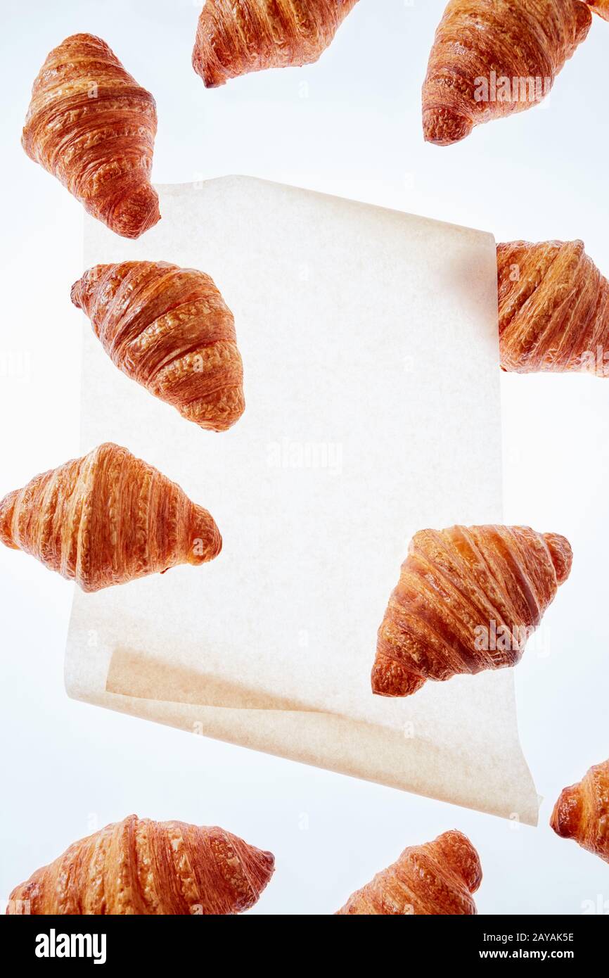 Floating freshly baked croissant on a light background of parchment ...