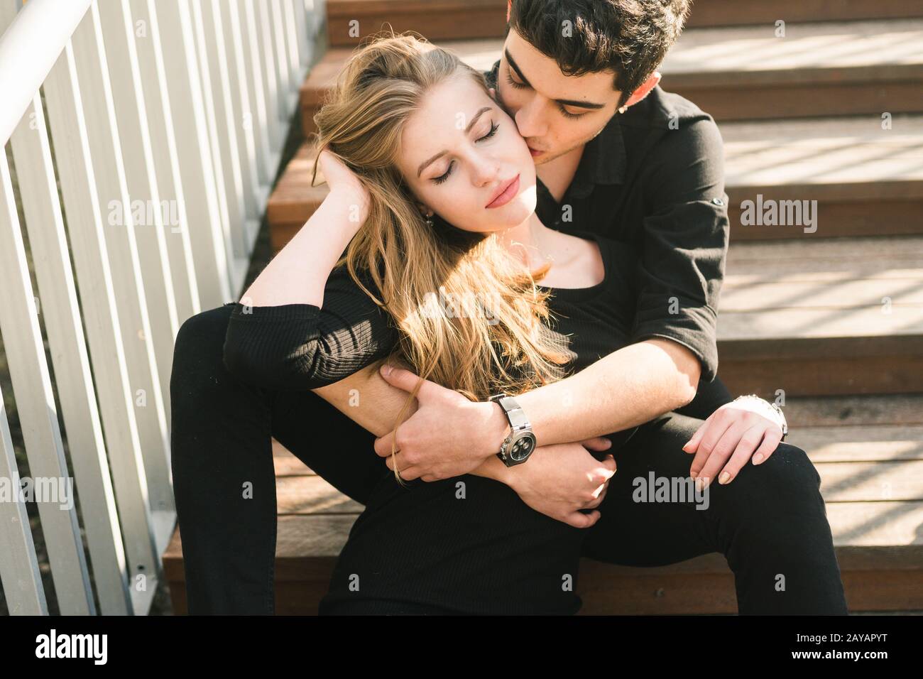 Beautiful young multiracial couple, student couple in love, sit wooden ...