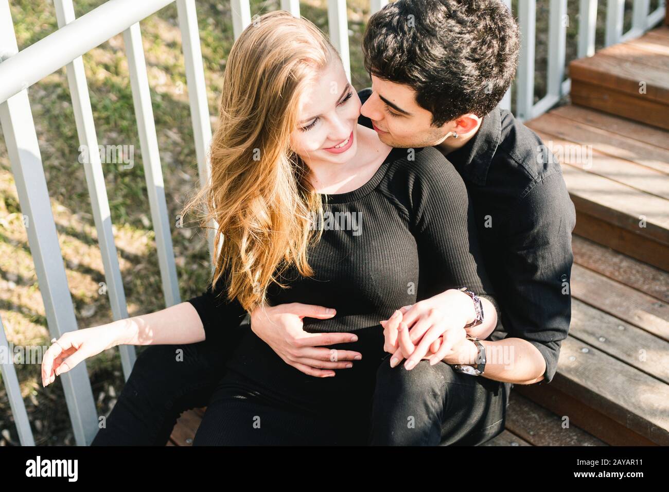 Beautiful young multiracial couple, student couple in love, sit wooden ...