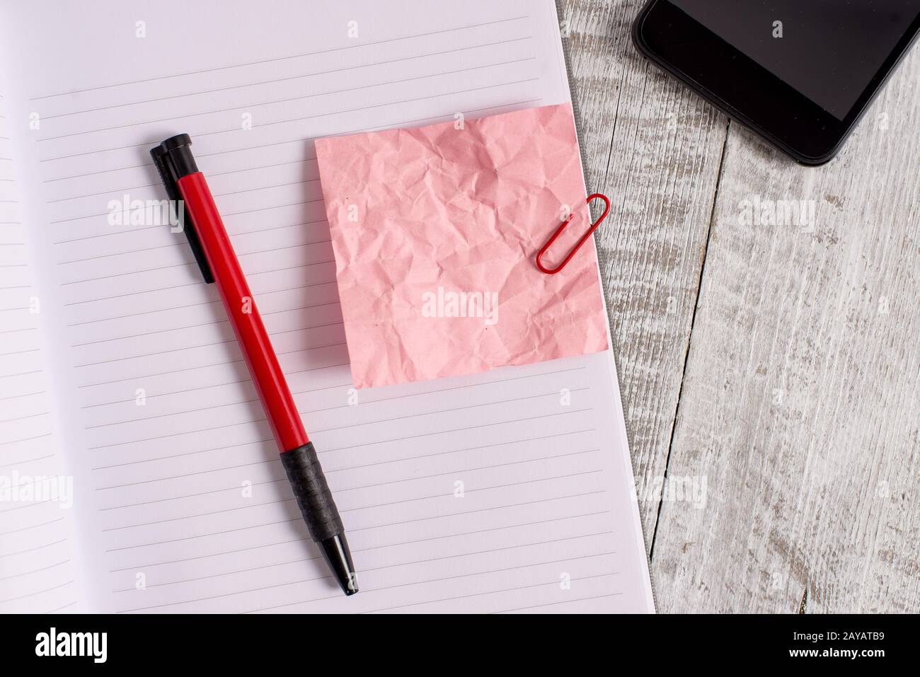 Crumpled note paper and a notebook placed above wooden table. Wrinkle ...