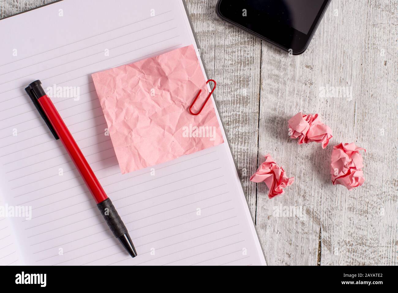Crumpled note paper and a notebook placed above wooden table. Wrinkle ...