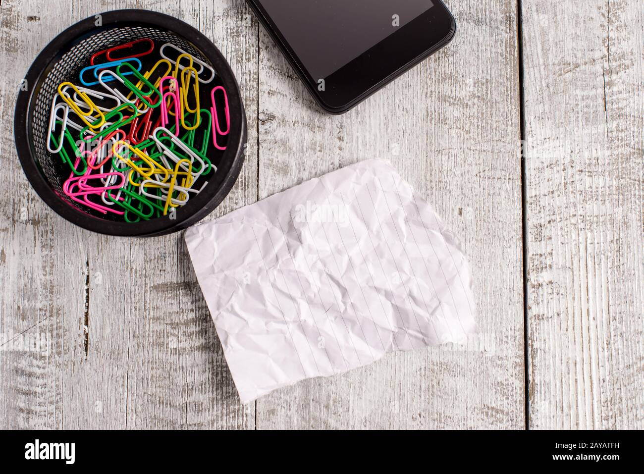 Crumpled note paper and clips placed above wooden table. Wrinkle sheet ...