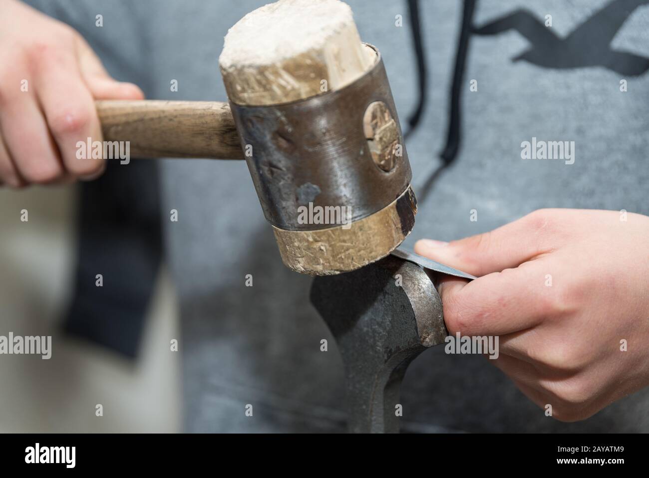 Craftsman works metal with mallet - closeup fold Stock Photo - Alamy