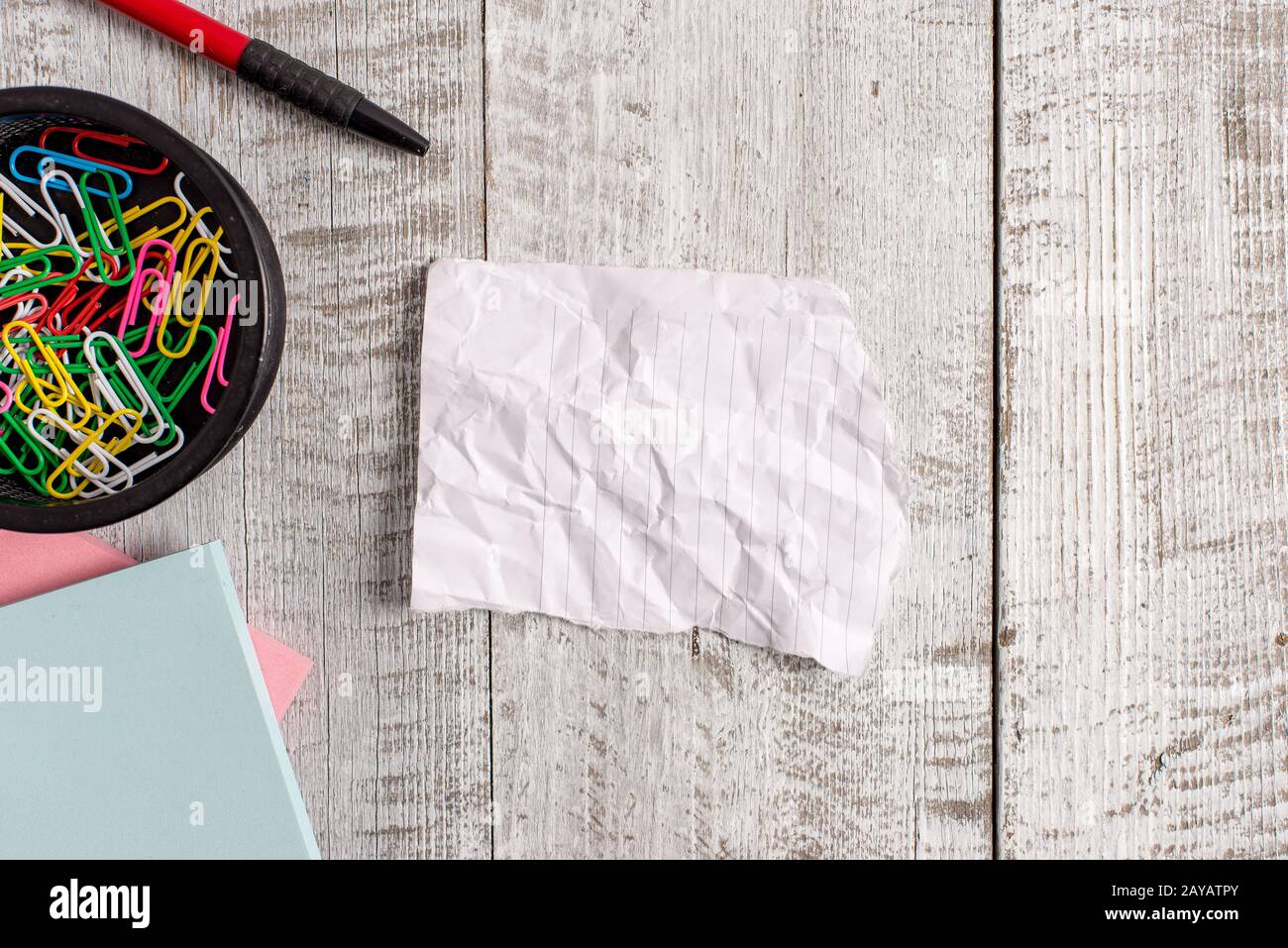 Crumpled note paper and clips placed above wooden table. Wrinkle sheet ...