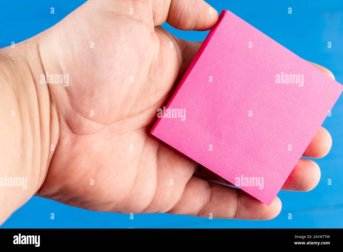Closed up view colored background man hand holding sticky note. Square ...