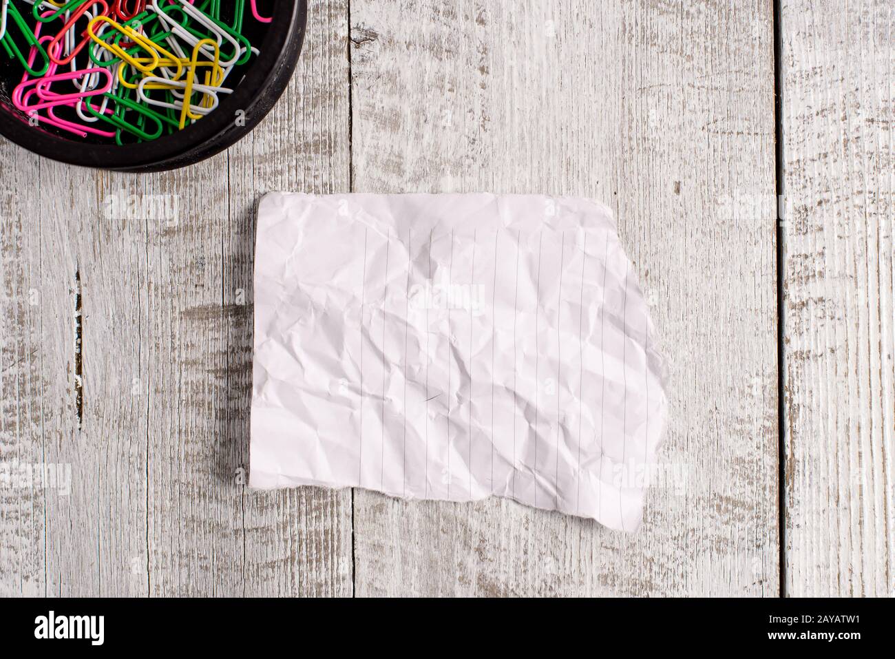 Crumpled note paper and clips placed above wooden table. Wrinkle sheet ...