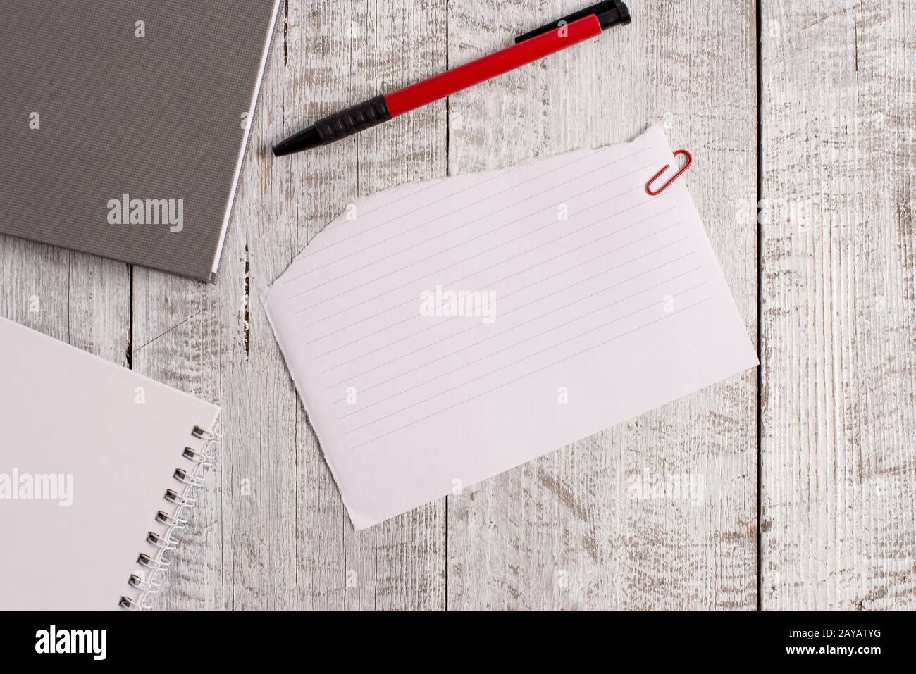 Torn paper and notebook sheet plus a pen placed on top of a wooden ...