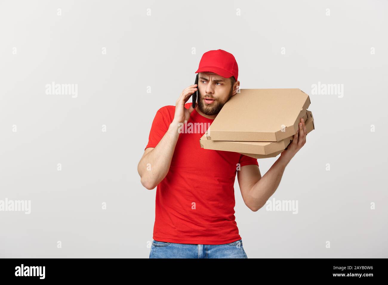 Delivery Concept: Handsome pizza delivery man talking to mobile with ...