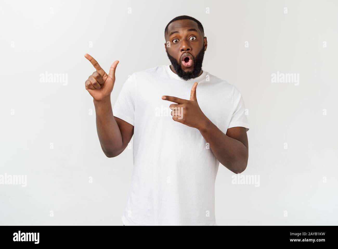 Young amazed African American pointing his finger at white background ...