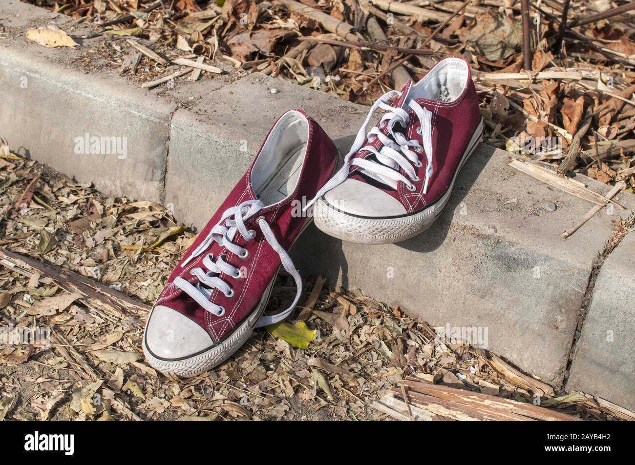 Pair of worn out vintage red old canvas sneakers on outside concrete ...